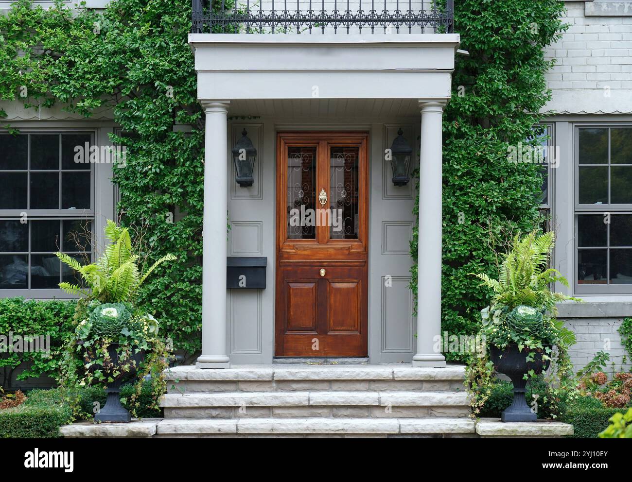 Vine covered house with portico entrance and elegant wood grain front ...