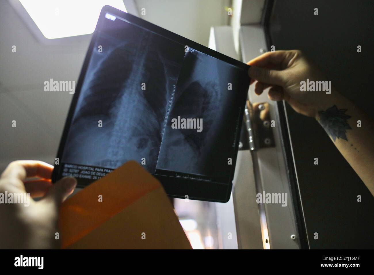 A medical staff looks at an X-ray under neon light. The hospital is ...