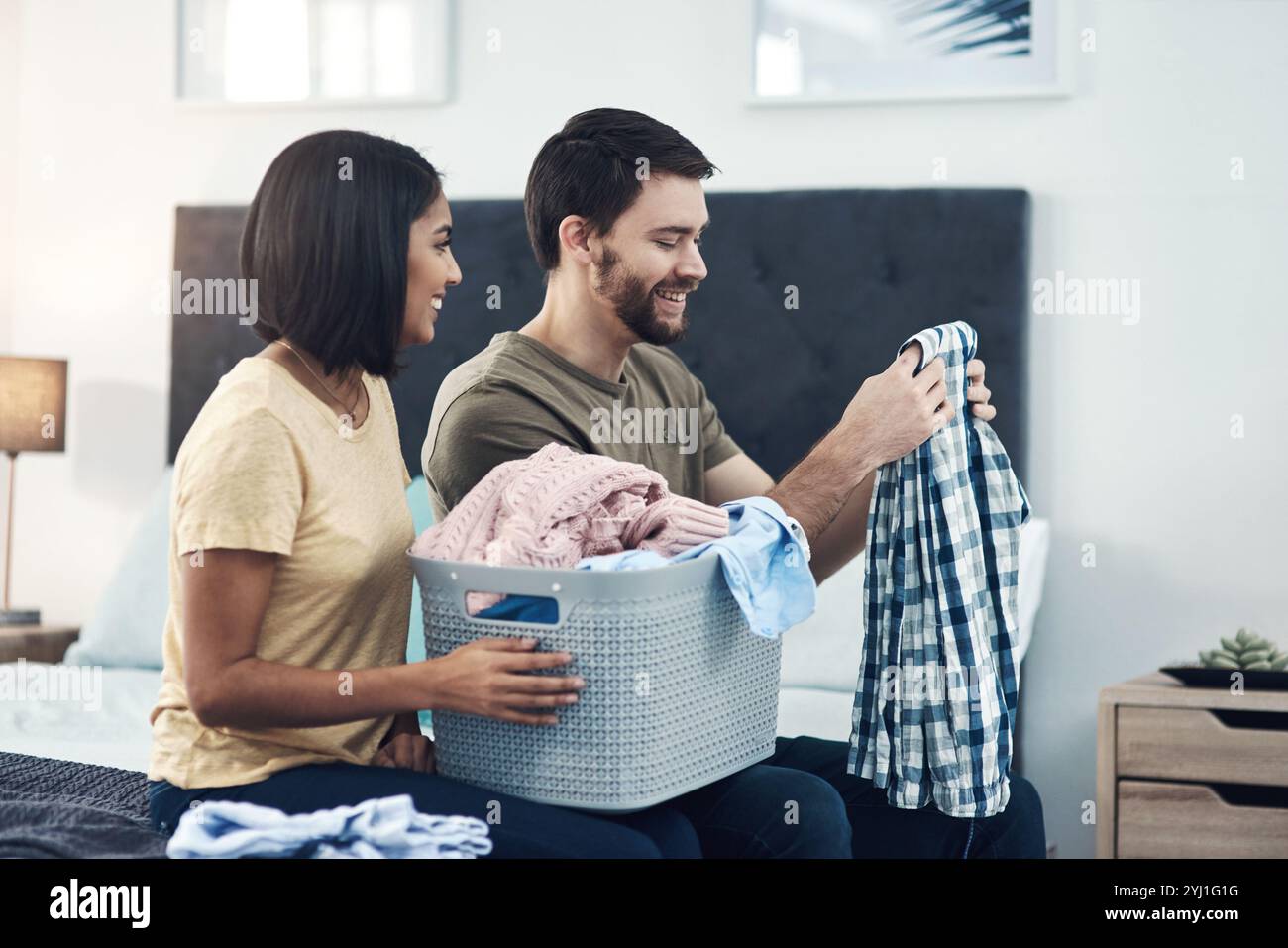 Happy couple, help and folding laundry on bed for support, shared ...