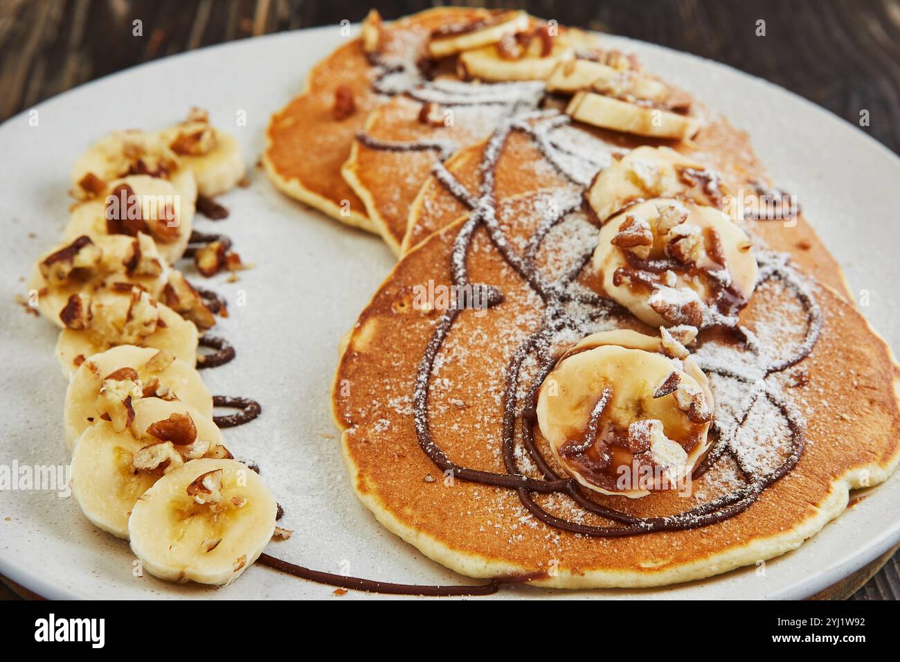 Delicious pancakes topped with sliced bananas, chopped nuts, and ...