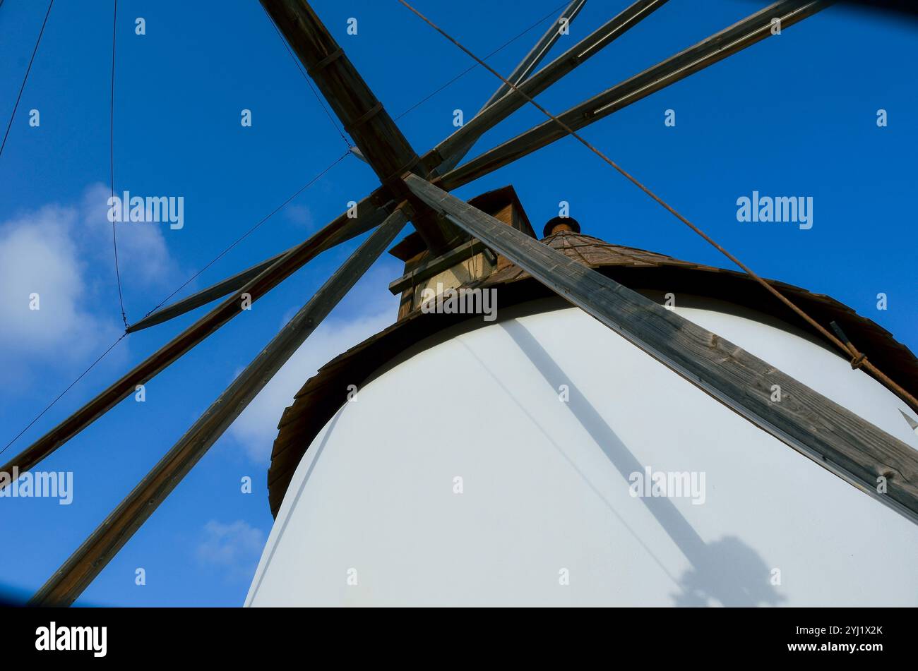 Wooden blades of a traditional white windmill are rotating against a ...