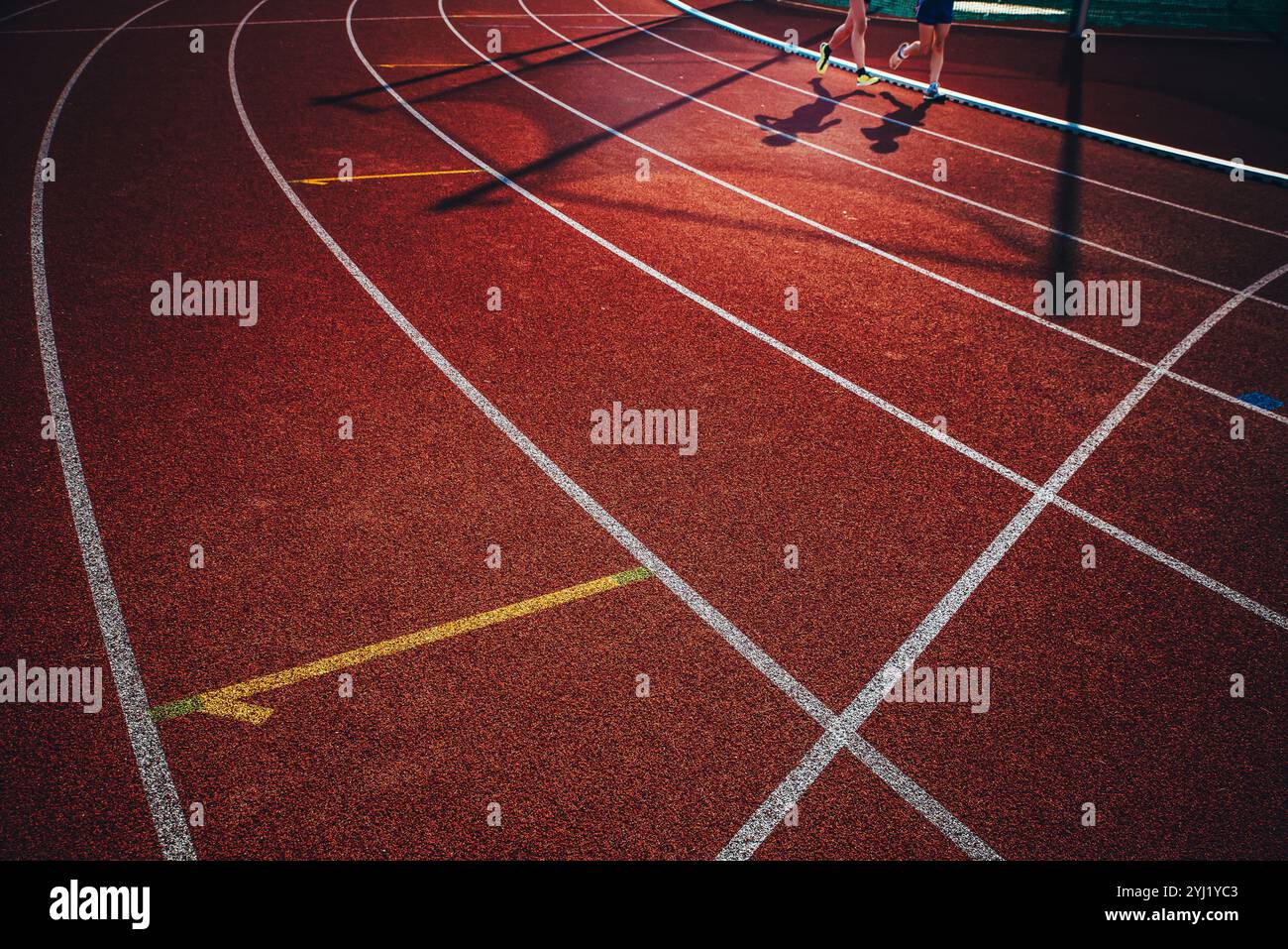 Legs of two runner and silhouette at modern track and field stadium ...