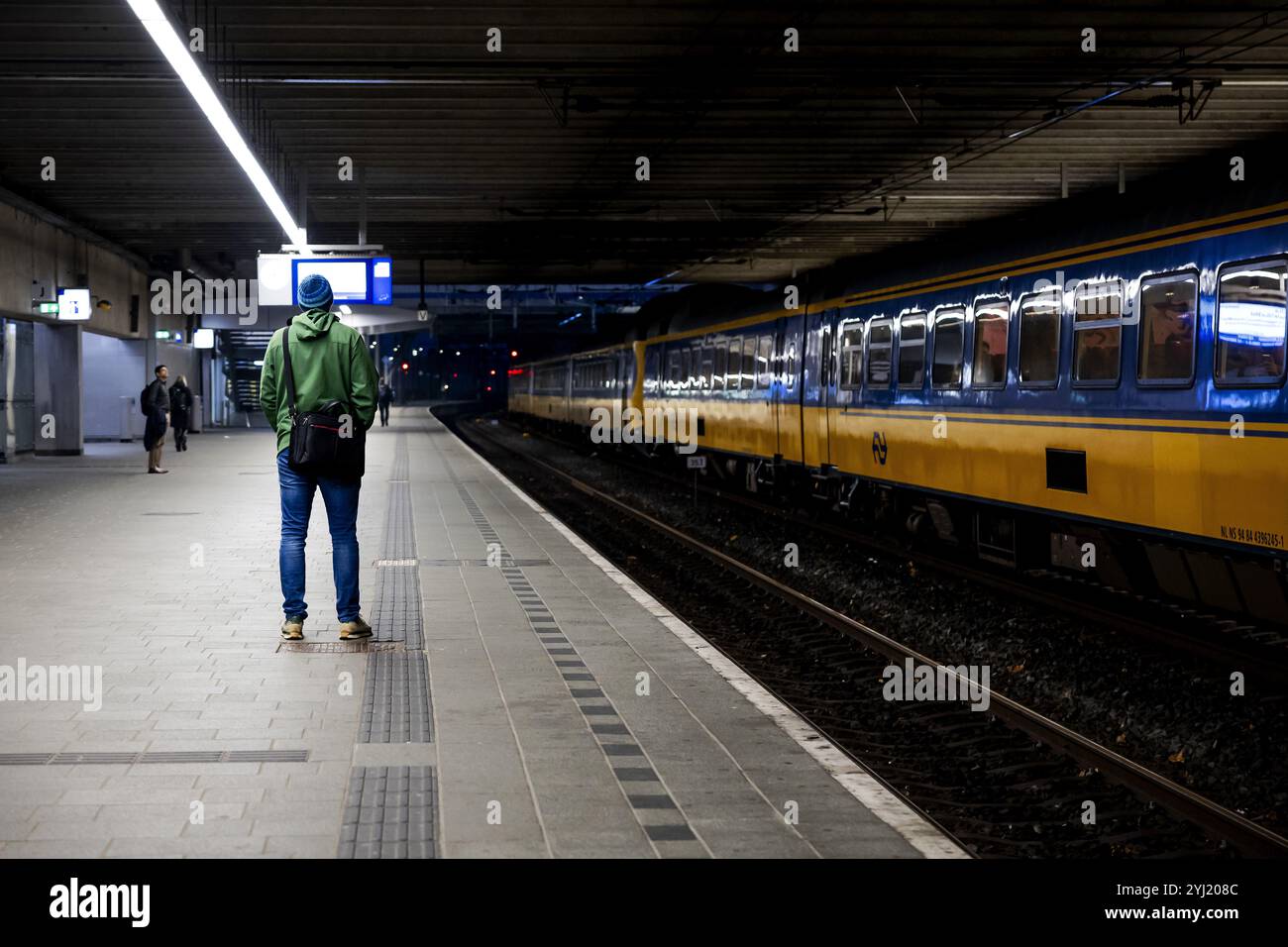 UTRECHT - A passenger on an empty platform where normally the train to ...