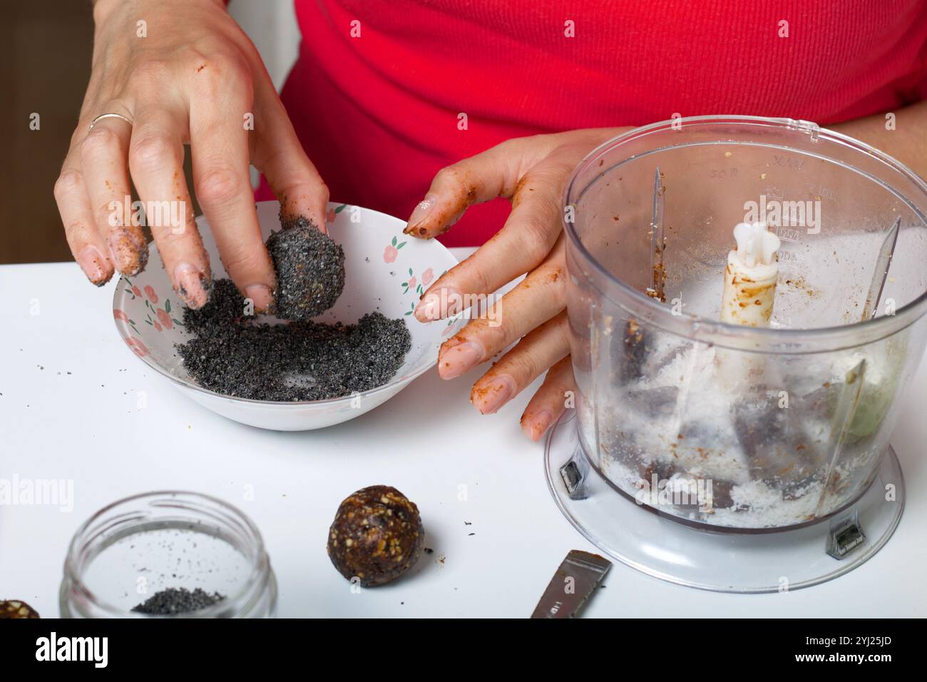 Woman makes candies from dried fruits. Balls of prunes, dates and ...