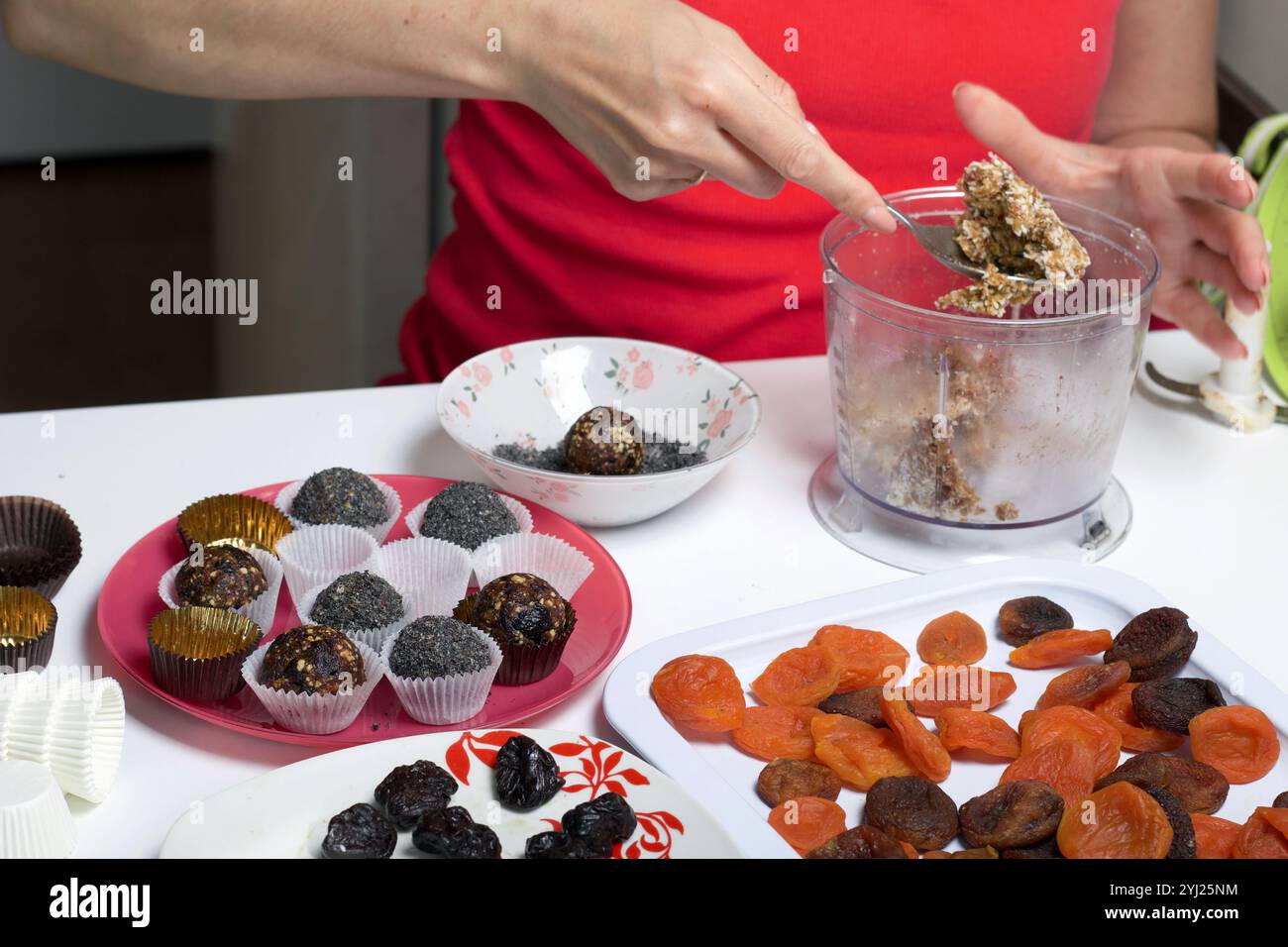 Woman makes candies from dried fruits. Balls of prunes, dates and ...