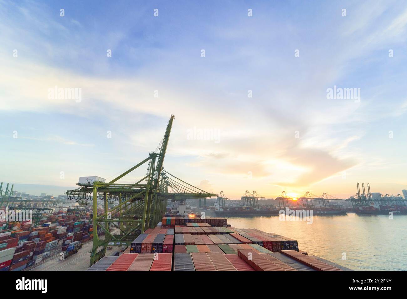 Sunrise over a busy container port with cranes and stacked shipping ...