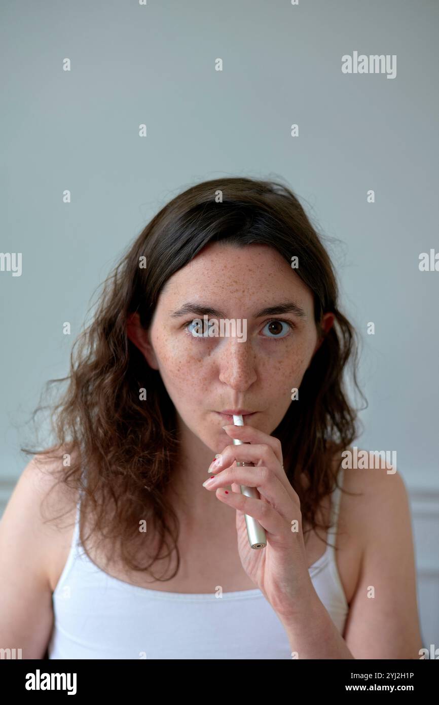 A young woman with freckles and curly hair smoking on a vapor Stock ...