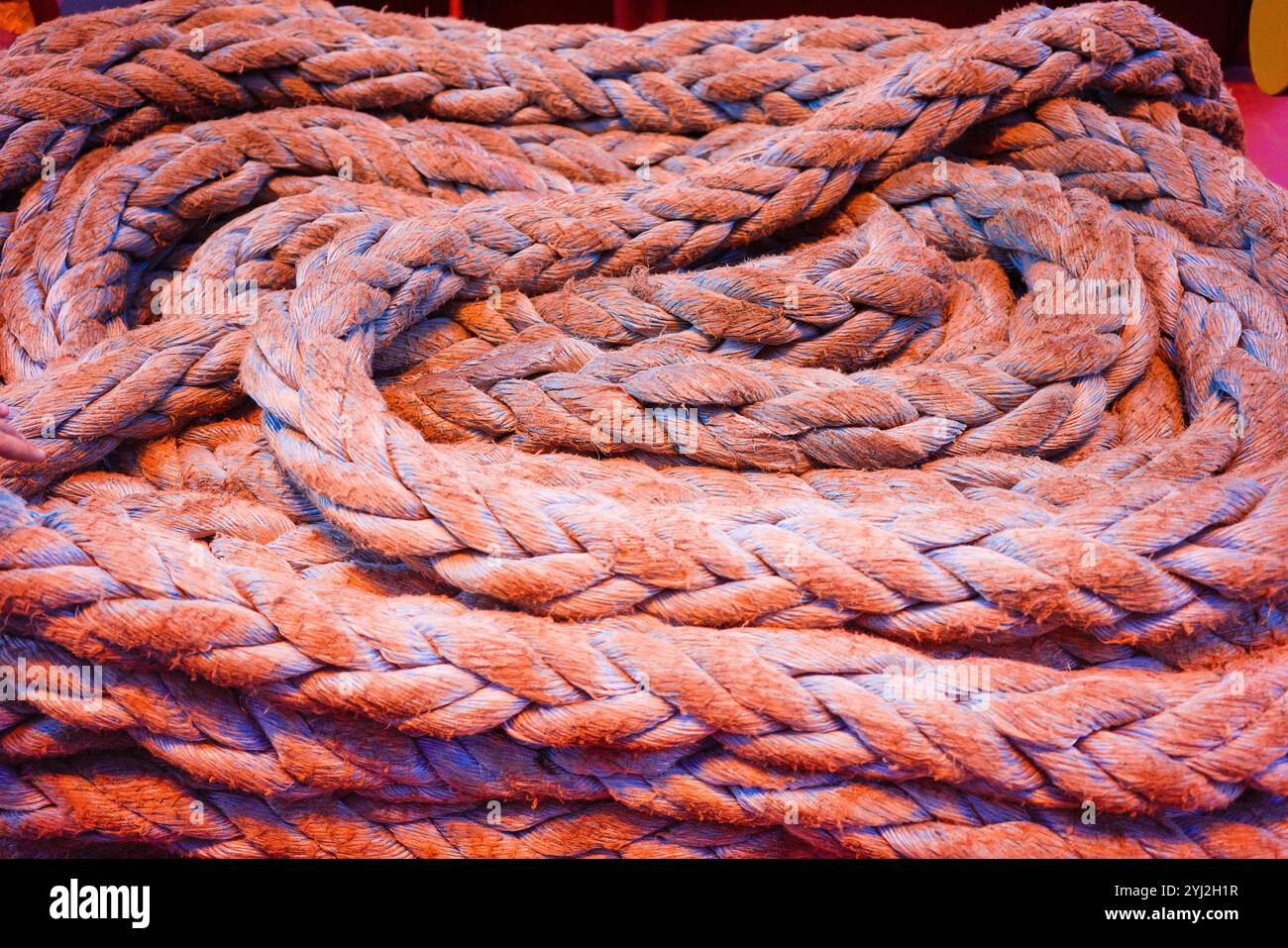 Twisted coils of thick brown rope in a heap on a cargo container ship ...