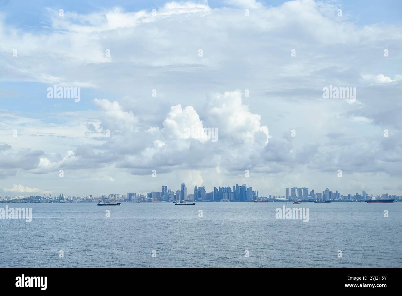 Panoramic view of a coastal city skyline under a cloudy sky with cargo ...
