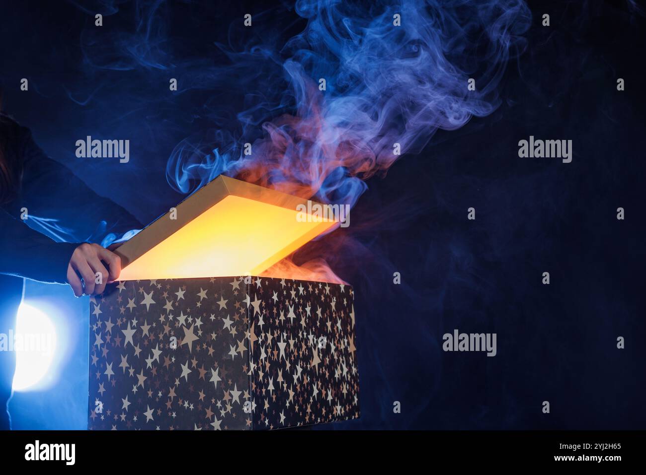 human hands taking out surprise from mysterious box on dark red ...