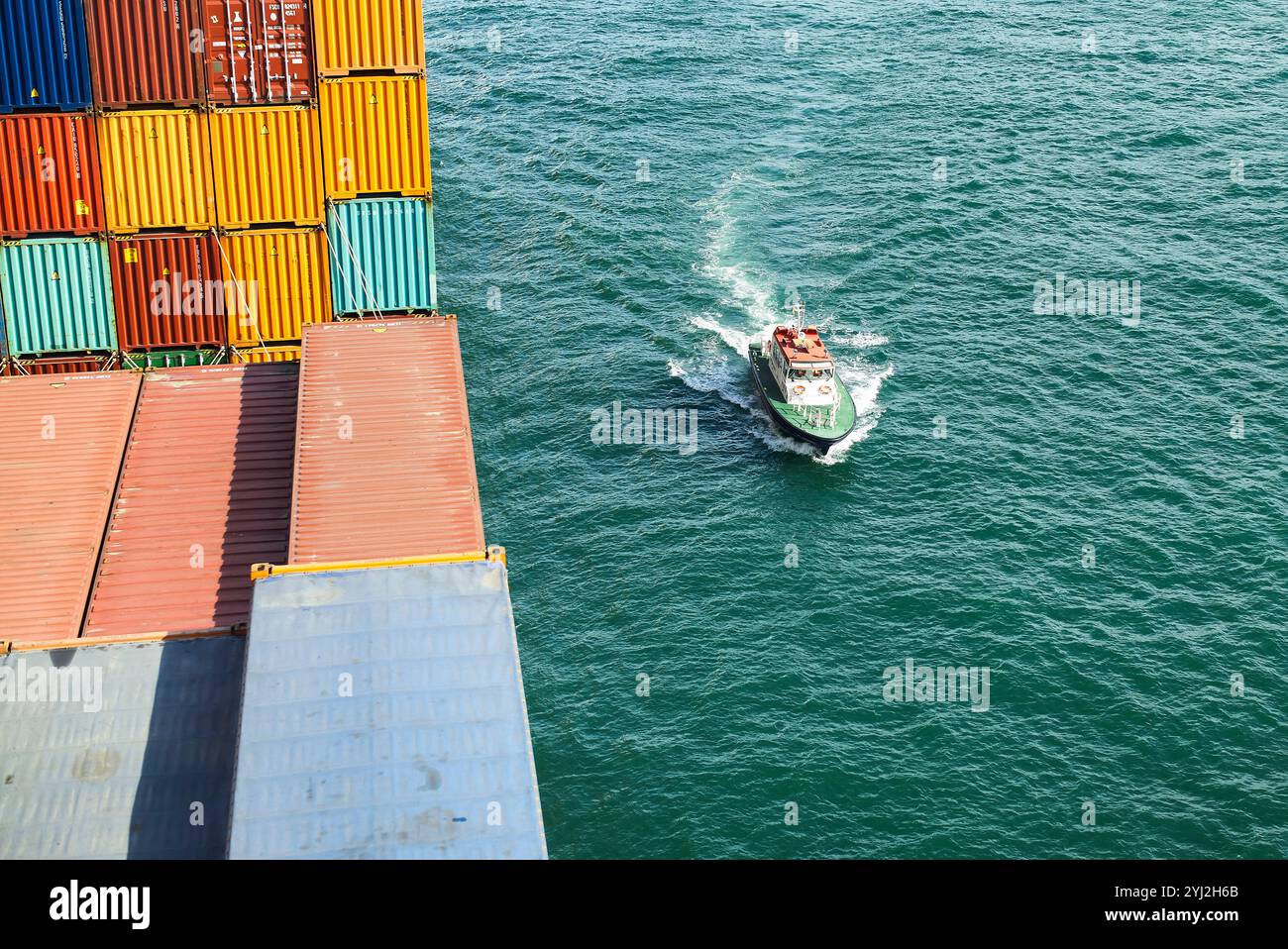 Aerial view of a large cargo ship transporting containers with a small ...