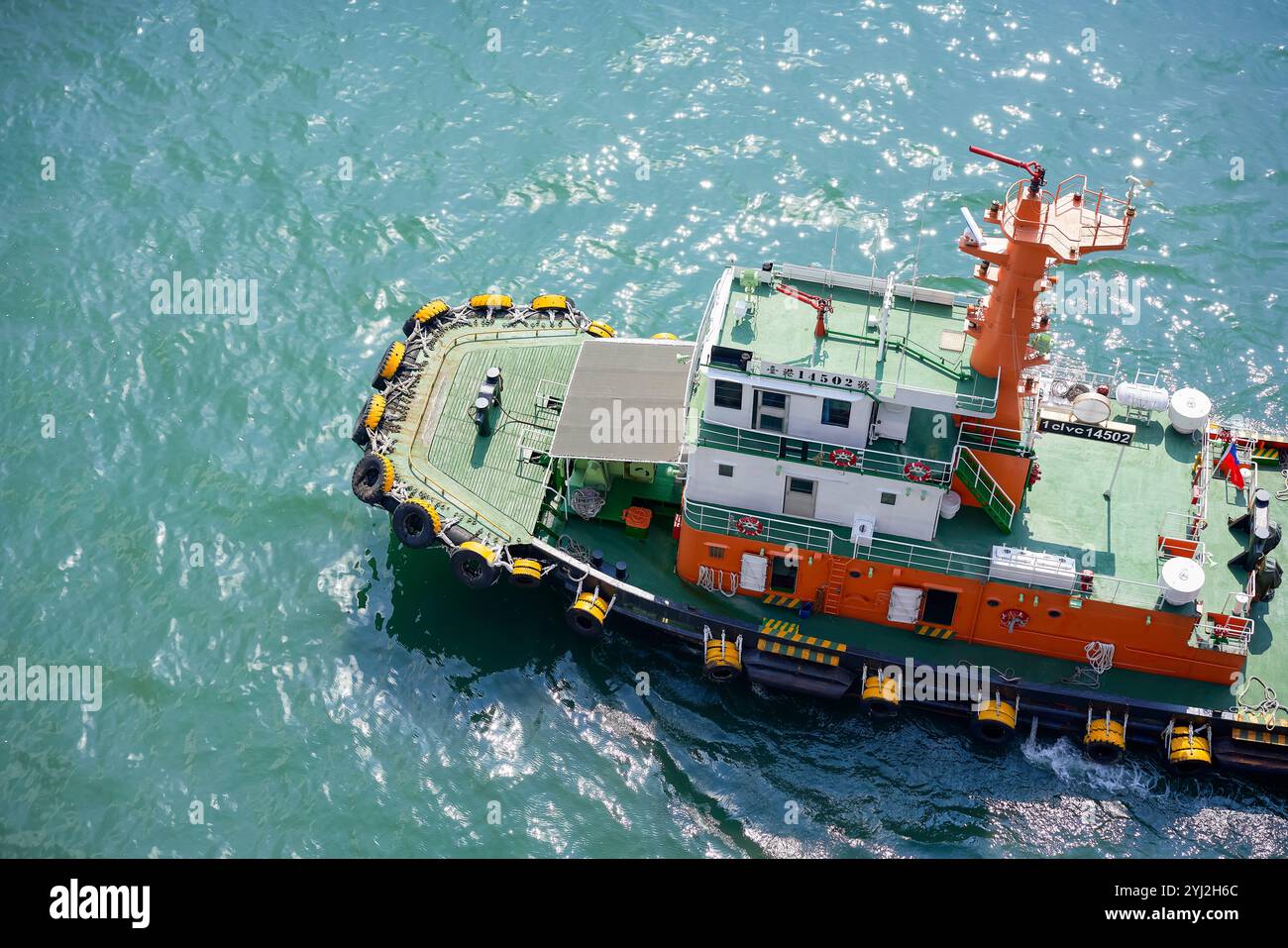 Aerial view of an orange and green tugboat on crystal blue waters ...