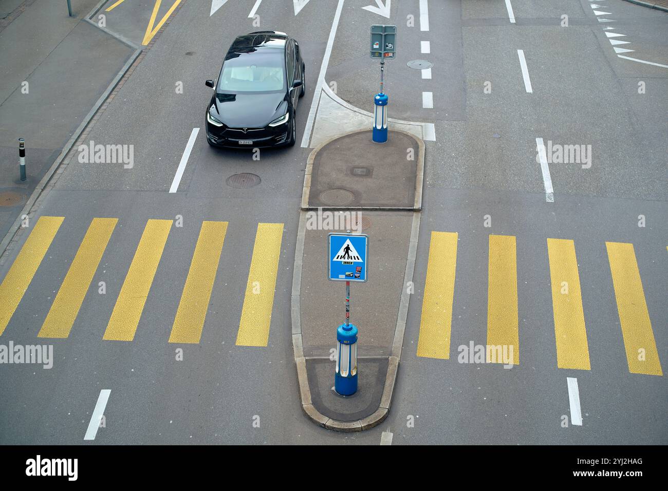 Aerial view of a black car stopped at a pedestrian crossing on a city ...
