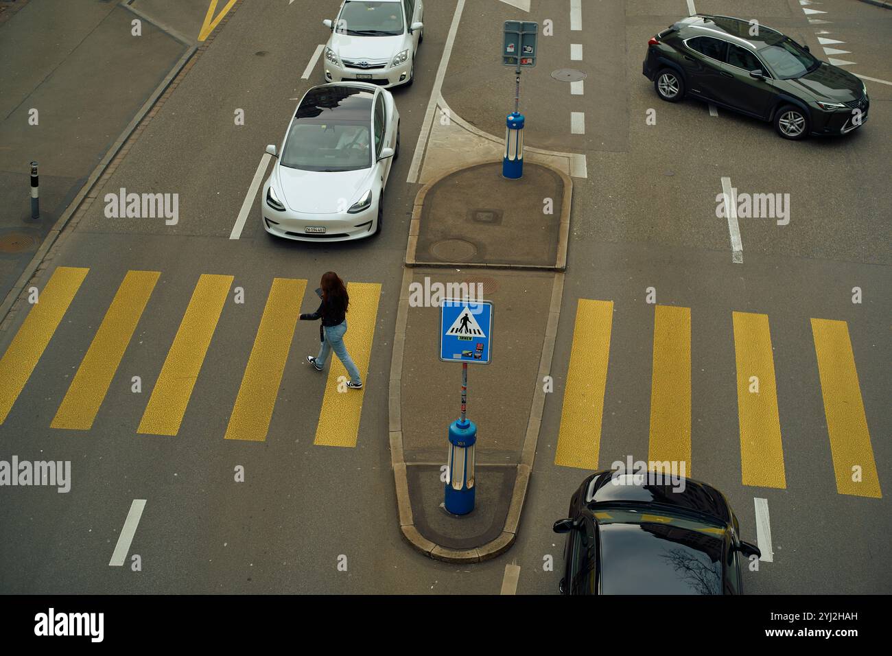 Elevated view of a pedestrian walking across a zebra crossing between ...