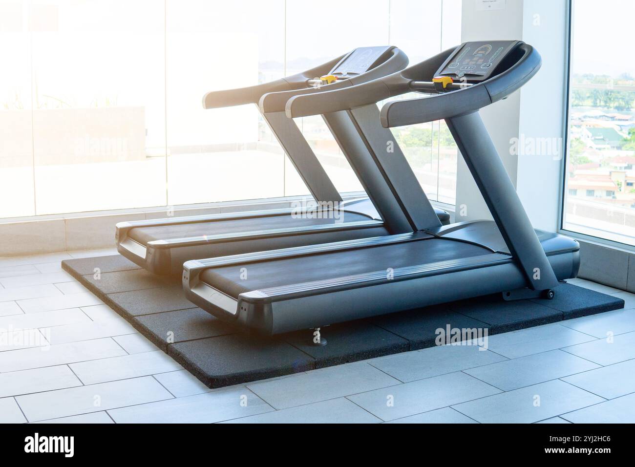 Two treadmills in a modern gym facing a large window with a city view ...