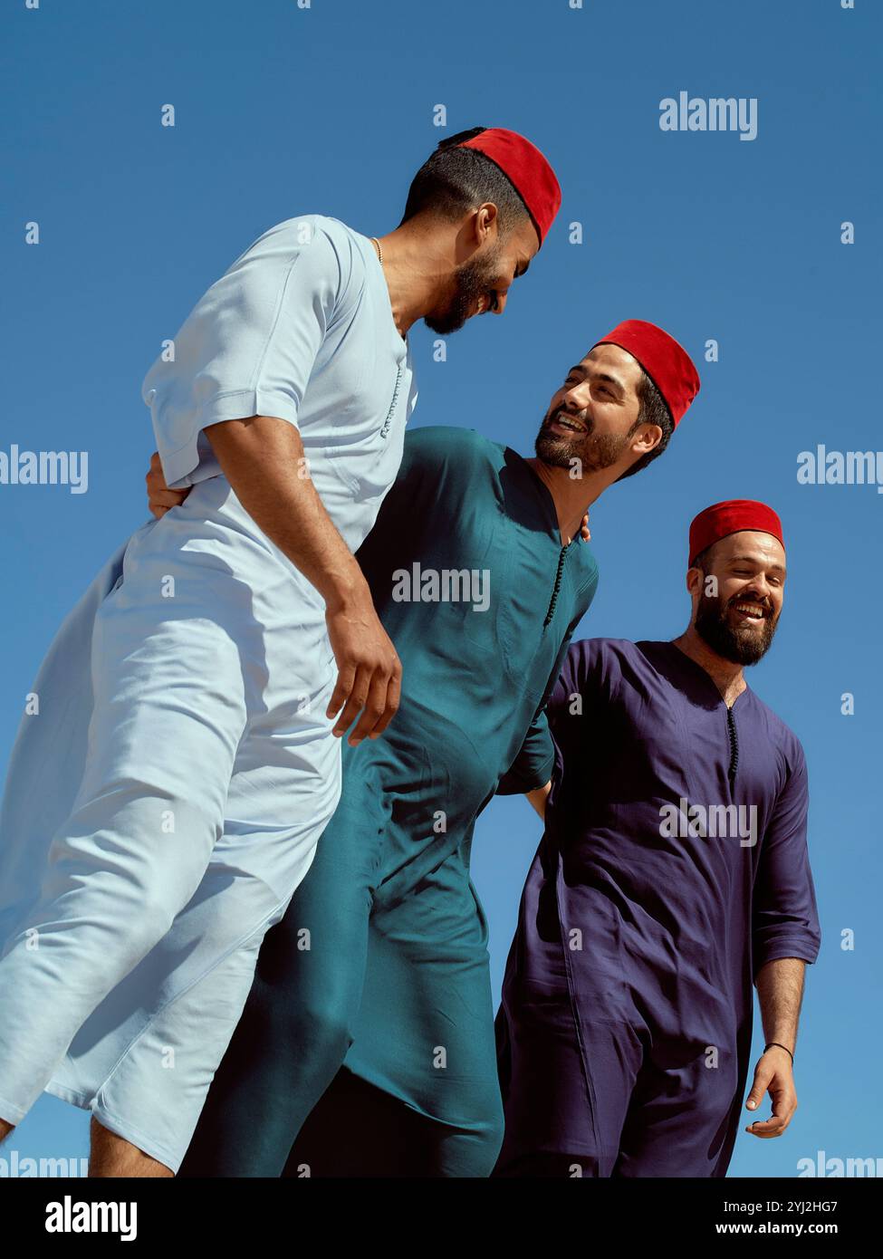 Three male healthcare workers in scrubs and surgical caps smile under a ...
