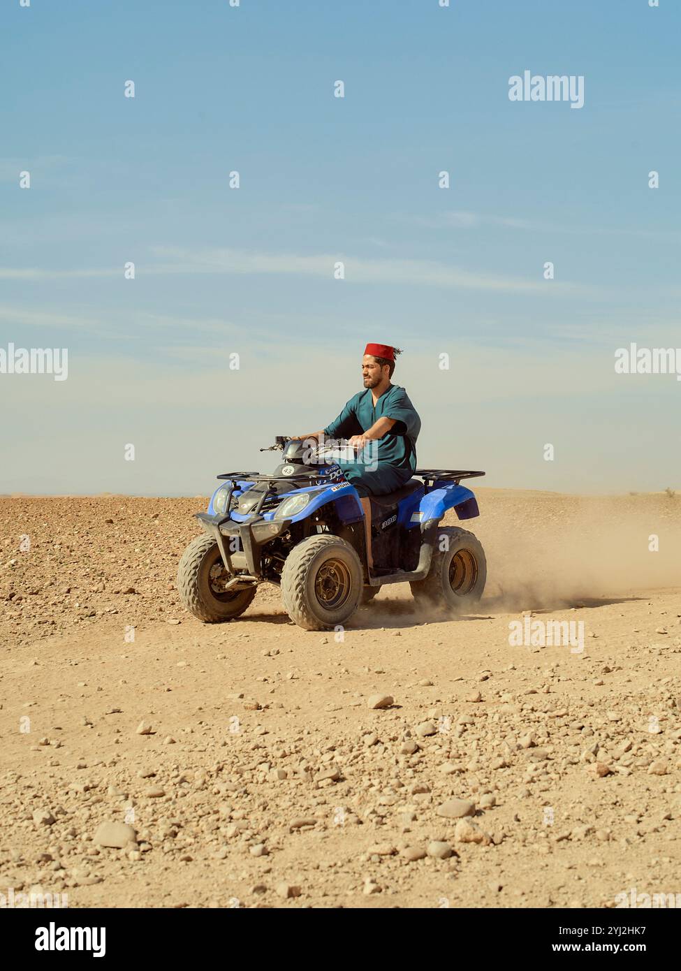 Man riding a quad bike in a desert setting, kicking up dust under a ...