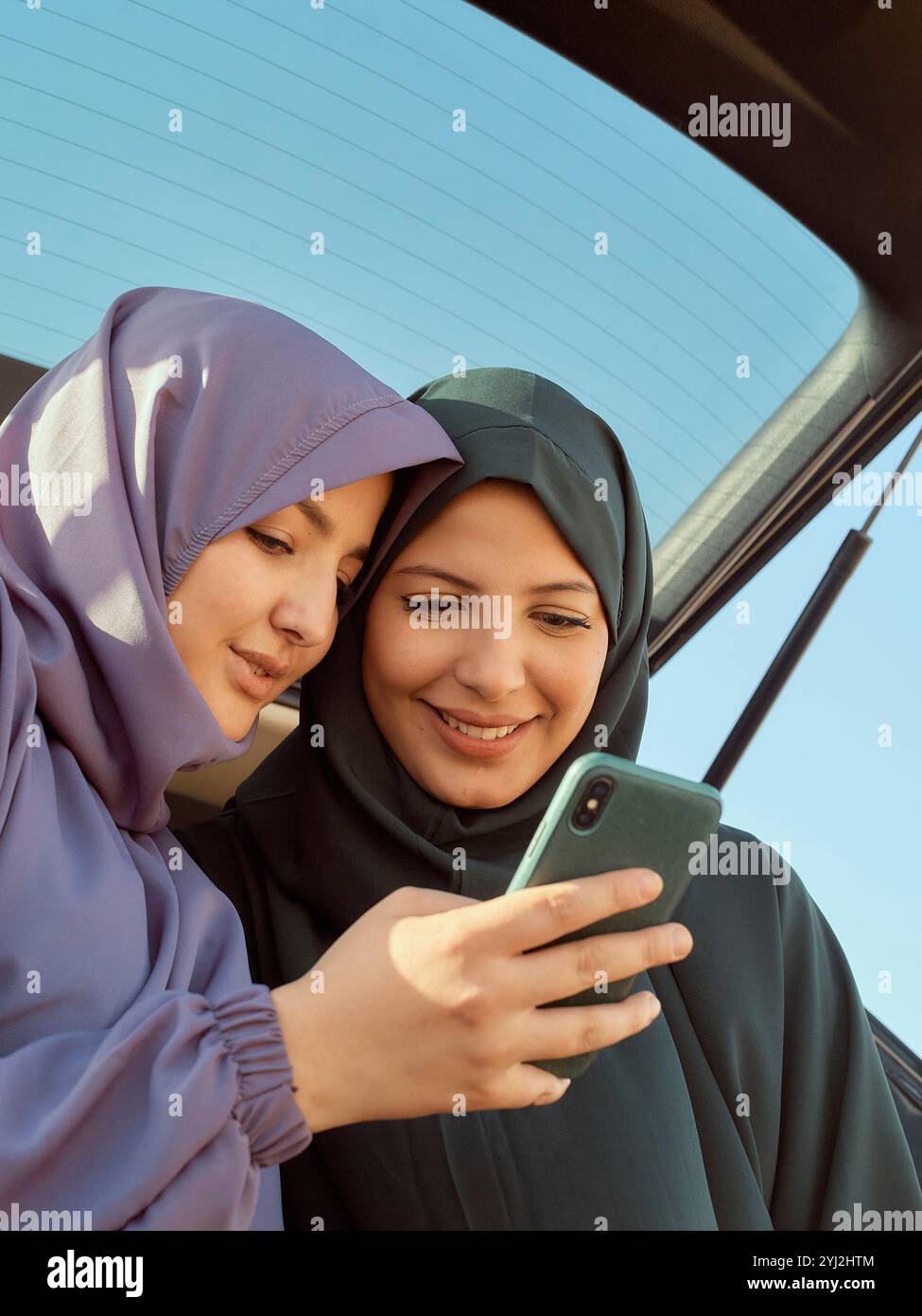 Two women hijabs smiling looking smartphone together outdoors hi-res ...