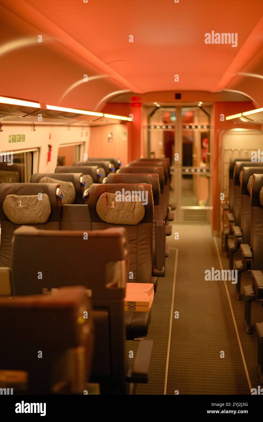 Empty train carriage interior with rows of seats illuminated by warm ...