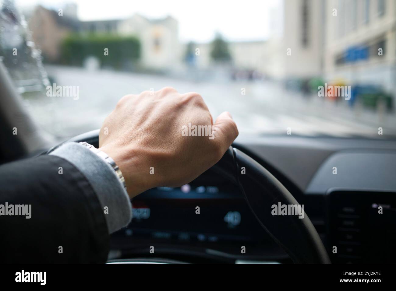 Close-up of a man's hand on the steering wheel of a car driving through ...