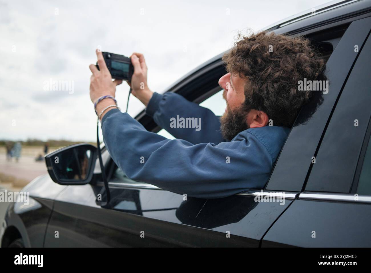 Adult man with curly hair taking a photo with his smartphone from the ...