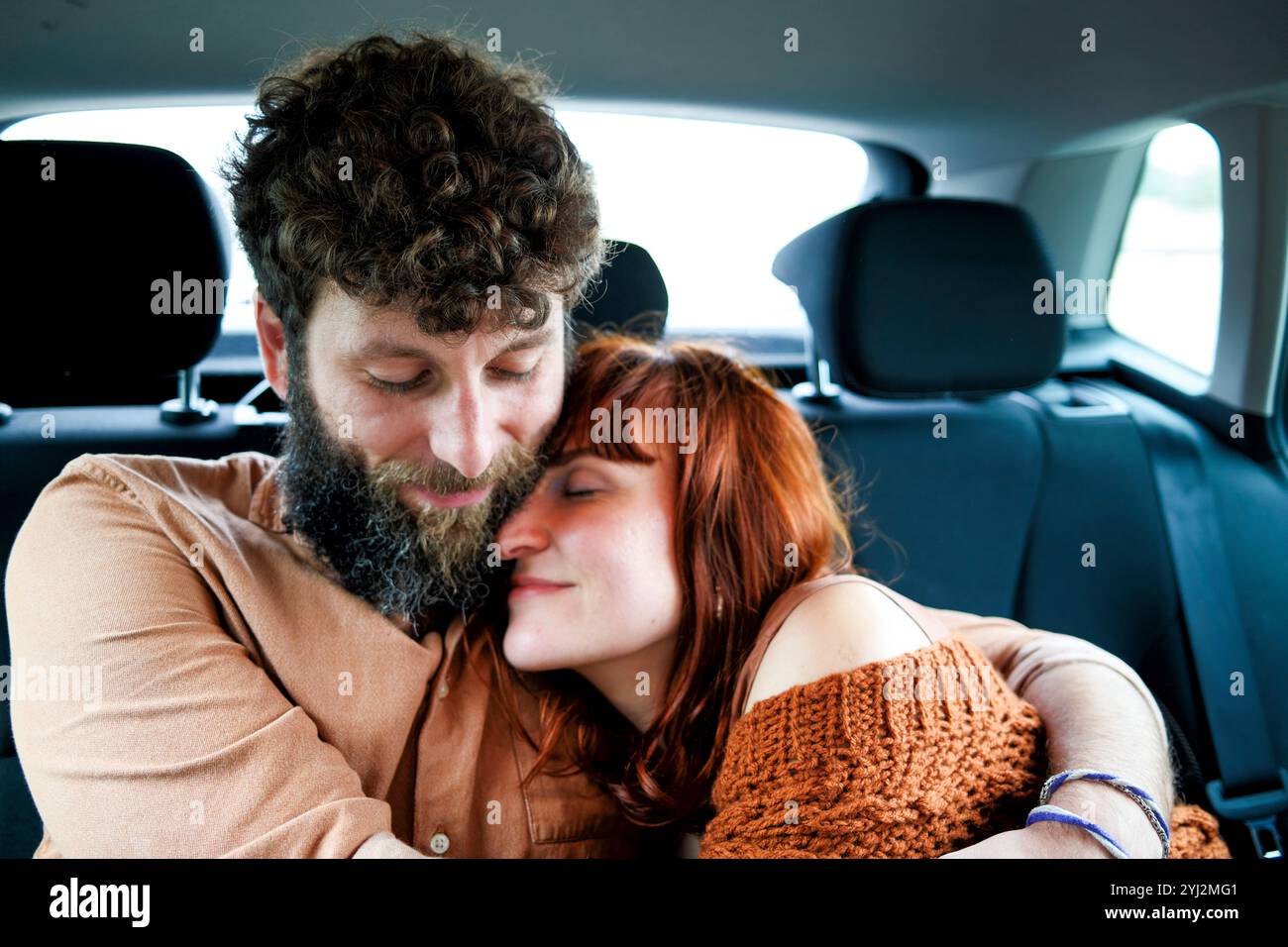 Couple embracing in a car with affectionate smiles and eyes closed ...