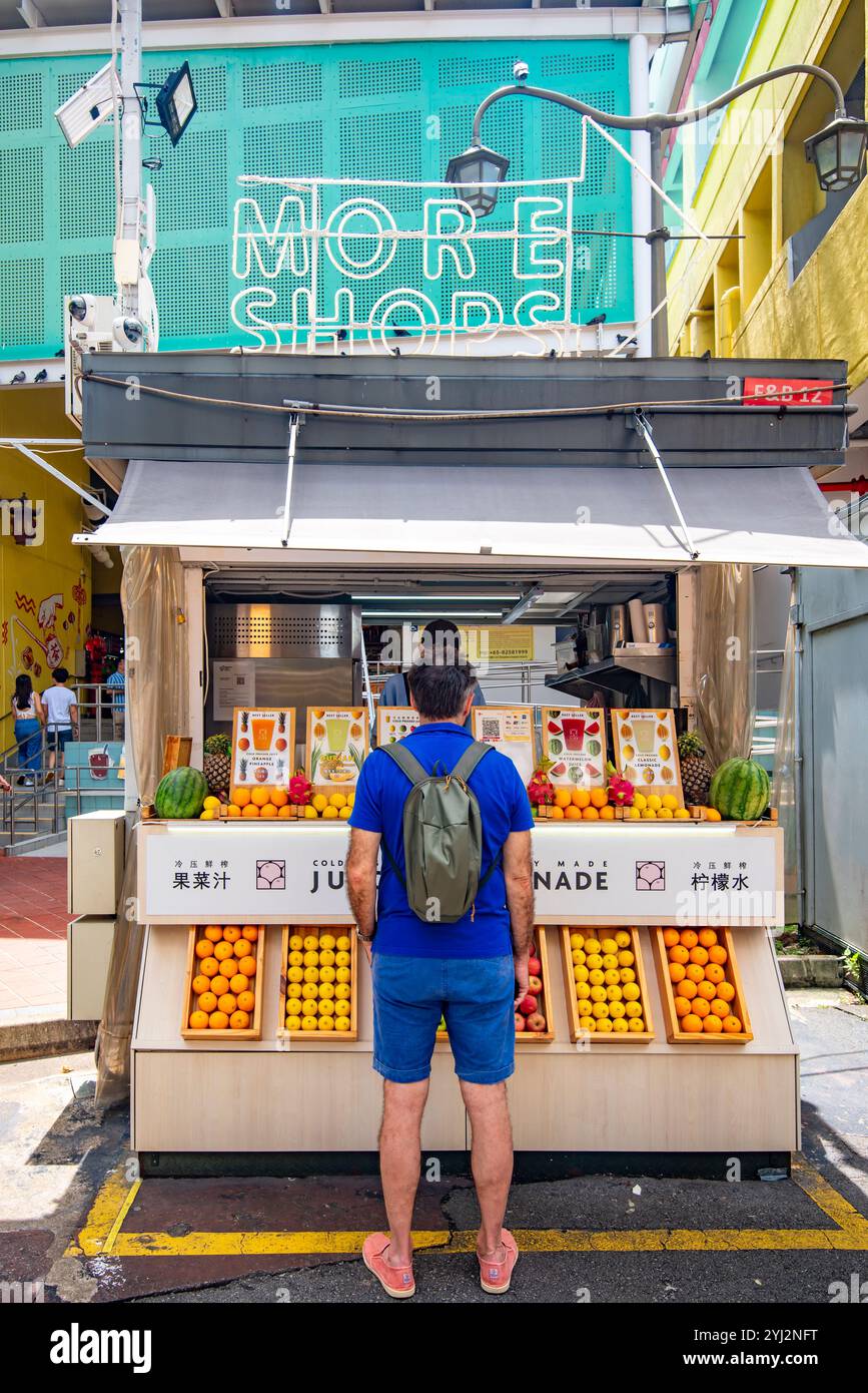 A non-Asian man wearing all blue, stands in front of a brightly ...