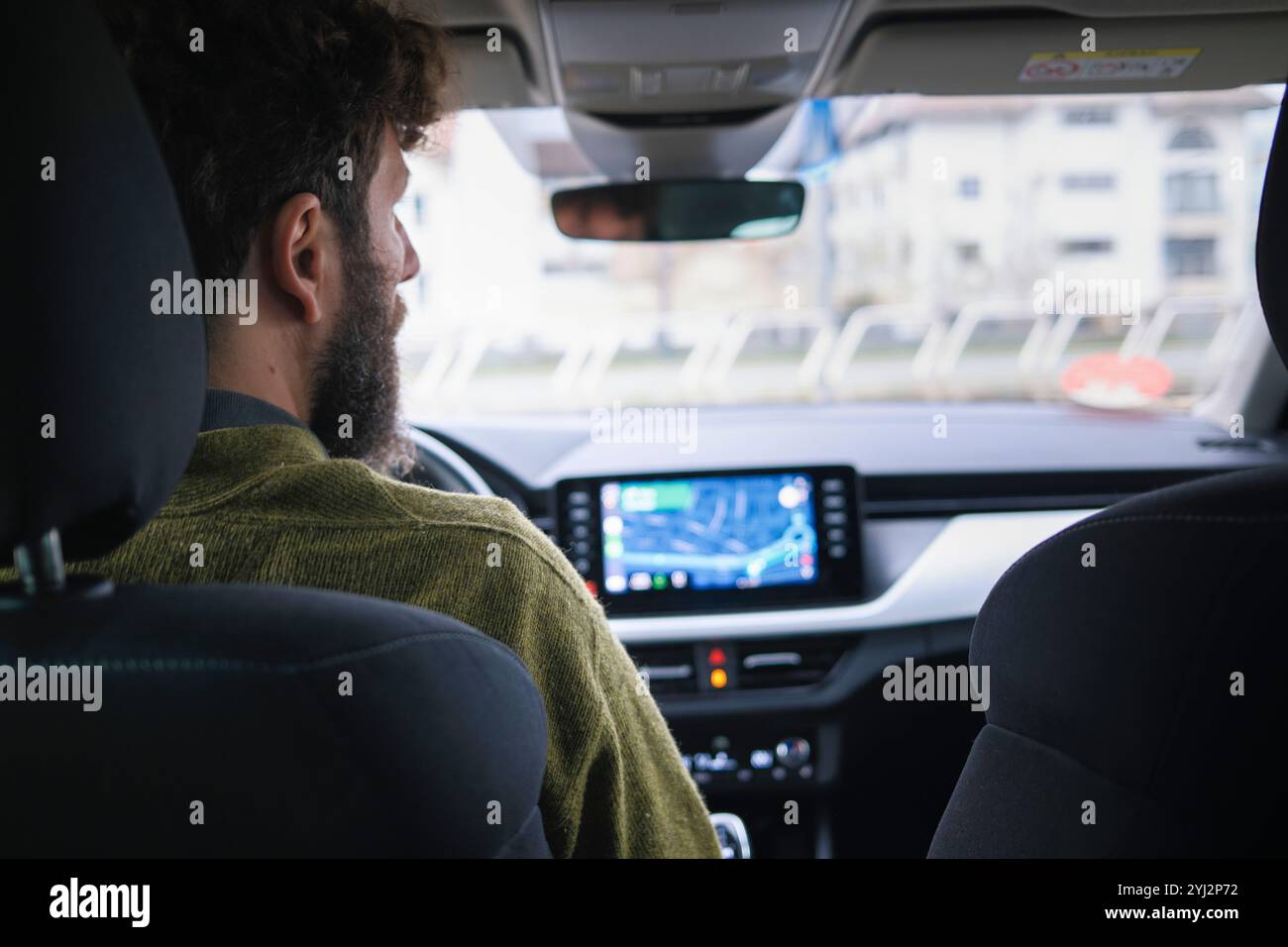 Man driving a car with a focus on the infotainment system and dashboard ...