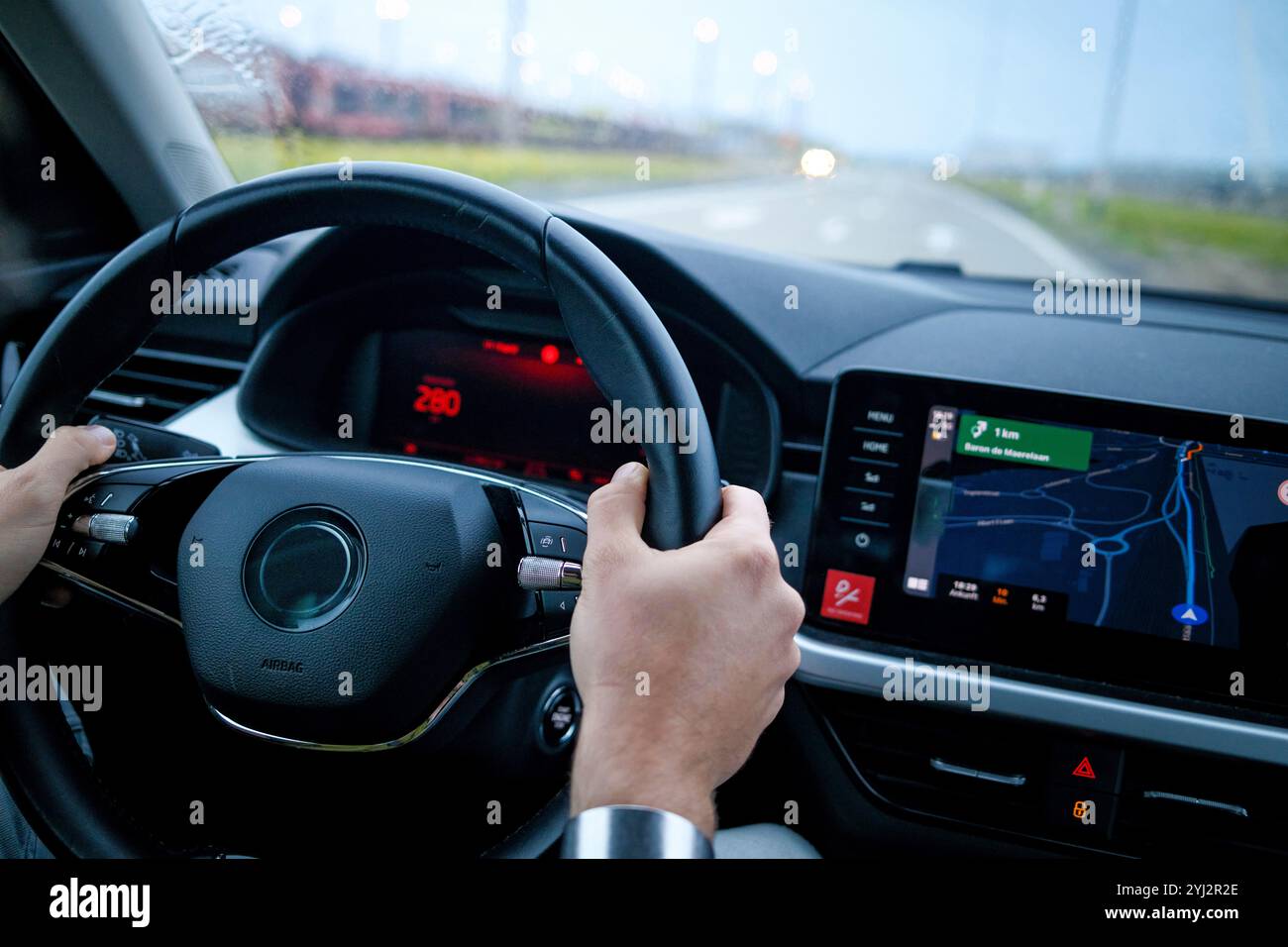 Close-up of a driver's hands on a steering wheel with a dashboard and ...