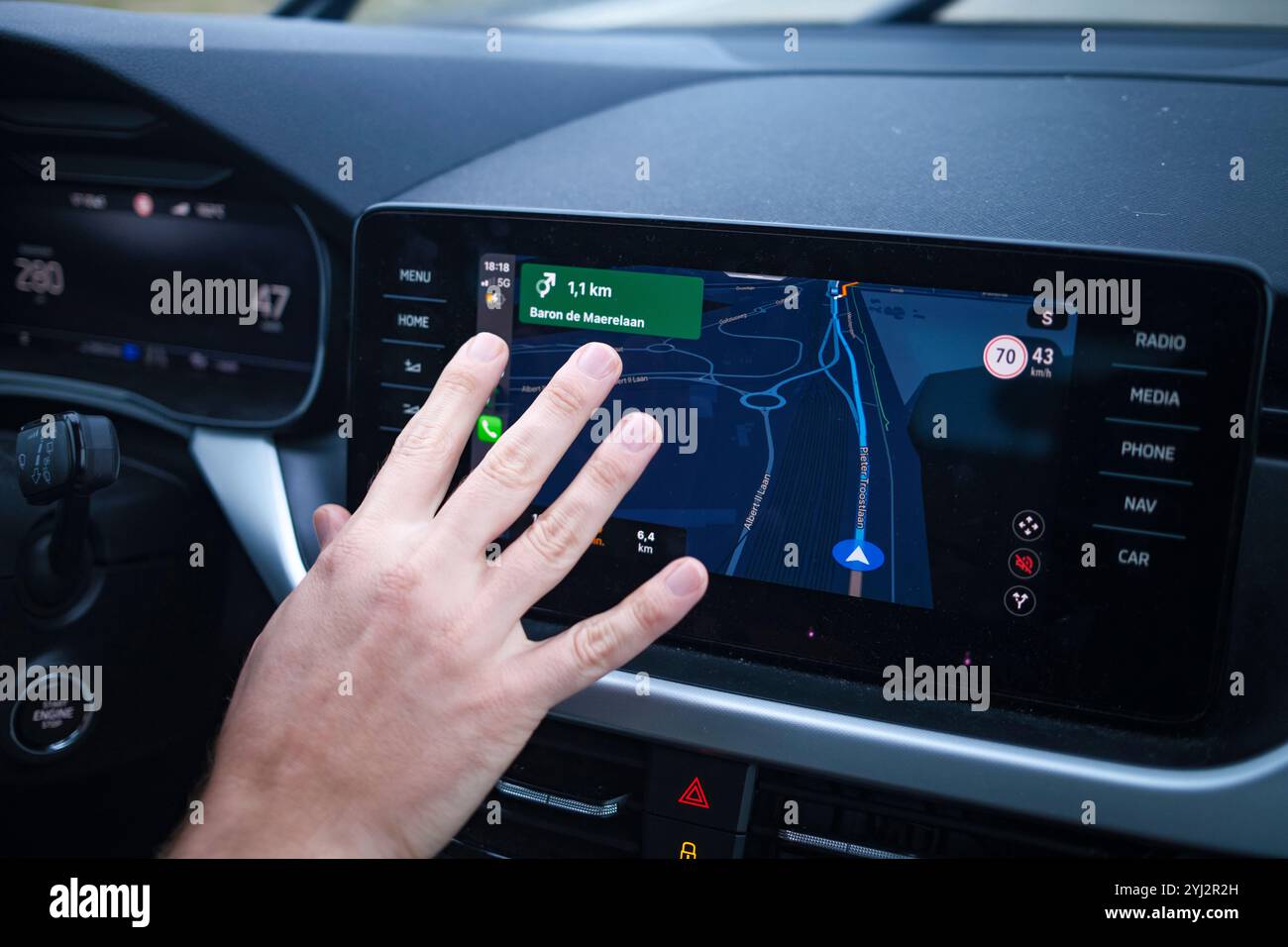 Hand interacting with a car's touchscreen navigation system showing a ...