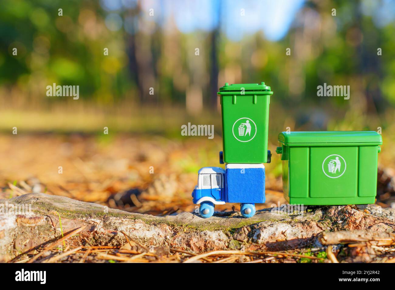 Miniature garbage truck with green bins placed on forest floor ...