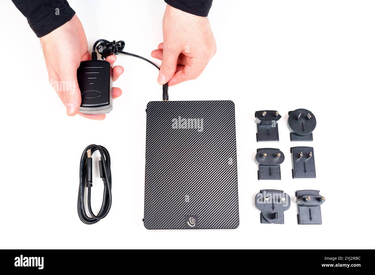 Kyiv, Ukraine - October 23, 2024: Hands connecting the power adapter to ...