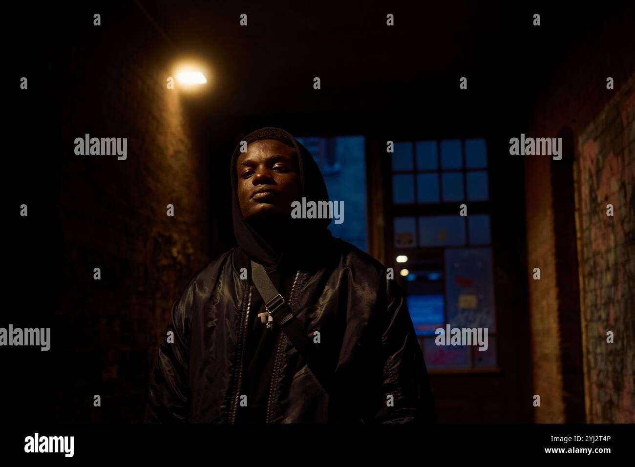 Silhouetted young man standing dimly lit urban alleyway night hi-res ...
