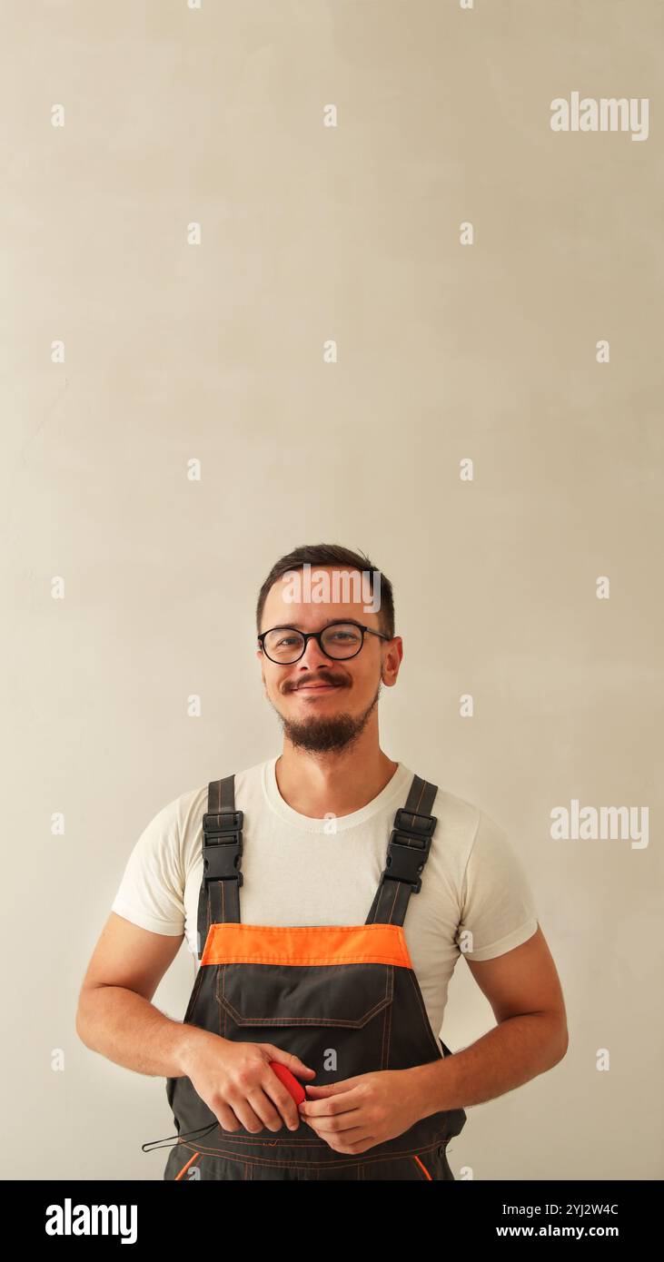 Vertical image of a man wearing an overall, standing in a construction ...