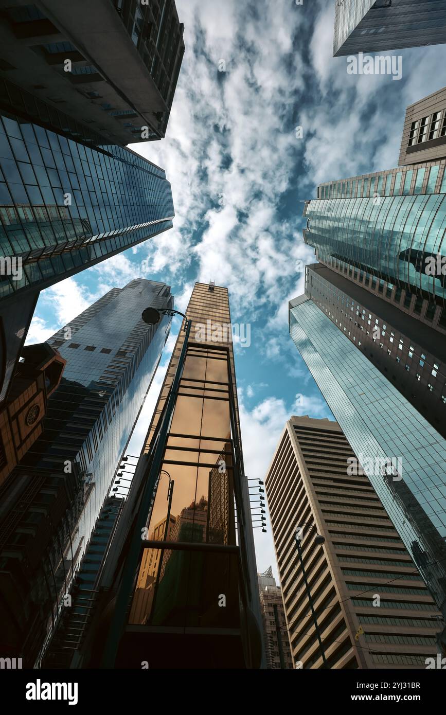 Modern skyscrapers rise high above as clouds drift across the blue sky ...