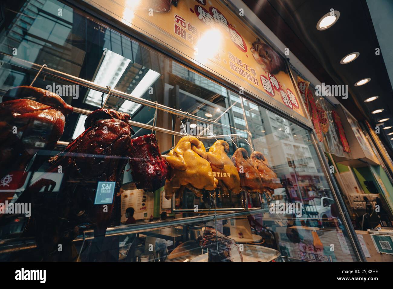 A fast food stall in Hong Kong showcases various roasted meats hanging ...