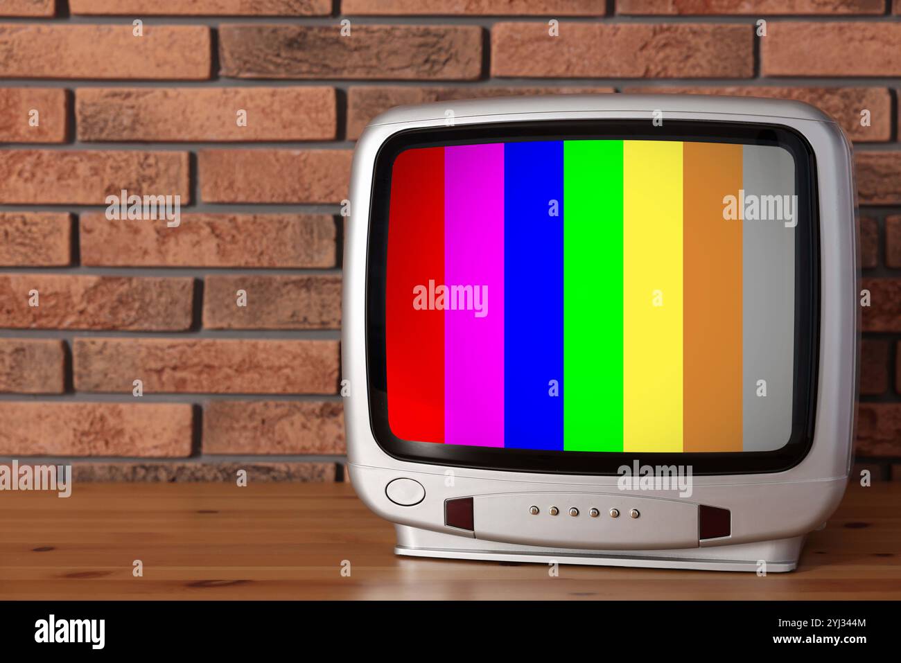 Retro TV set with test pattern on wooden table near brick wall. Color ...