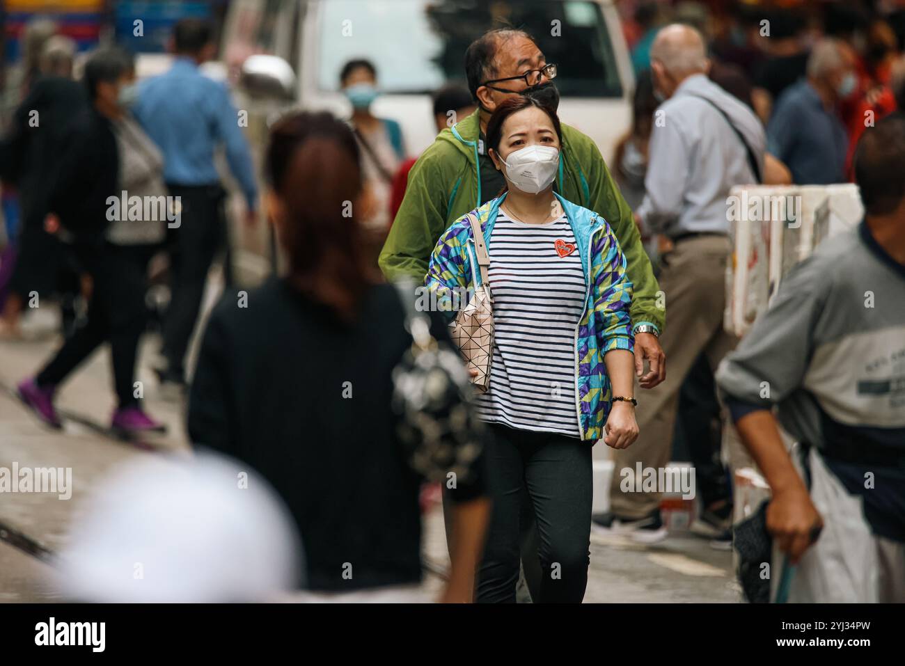 Pedestrians walk through a bustling street in central Hong Kong, many wearing masks as they go ...