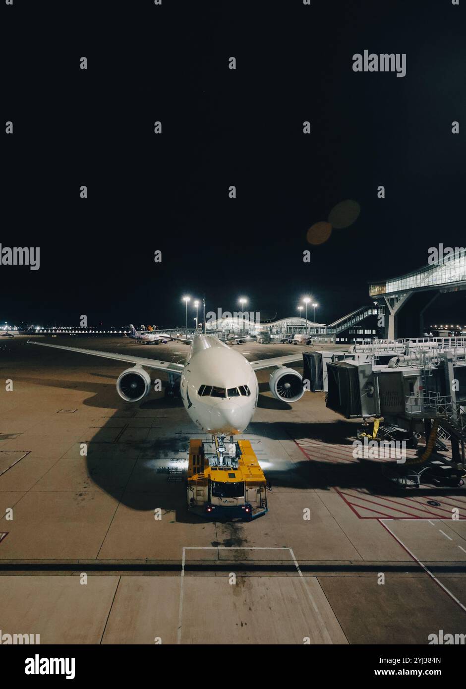 A large aircraft is parked at a gate in Hong Kong, with ground crew ...