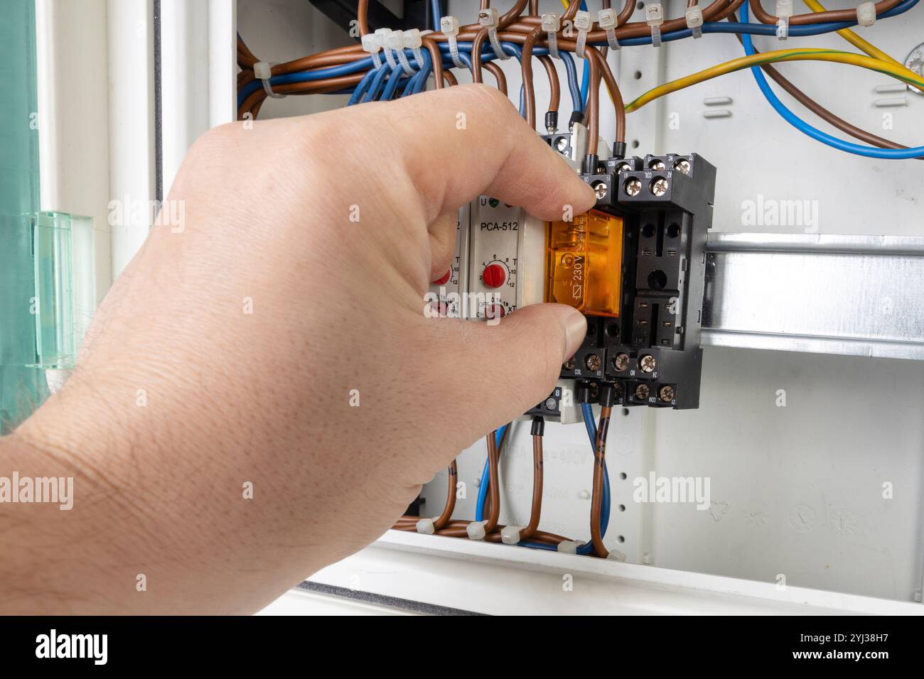 Close up of a hand inserting an electrical relay into a control panel ...