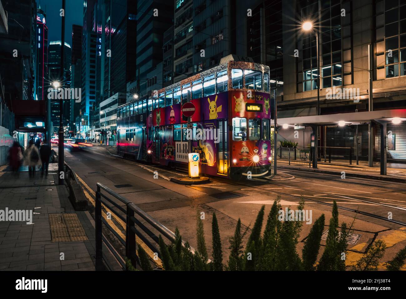 A vibrant tram travels along a busy street in Hong Kong, illuminated by ...