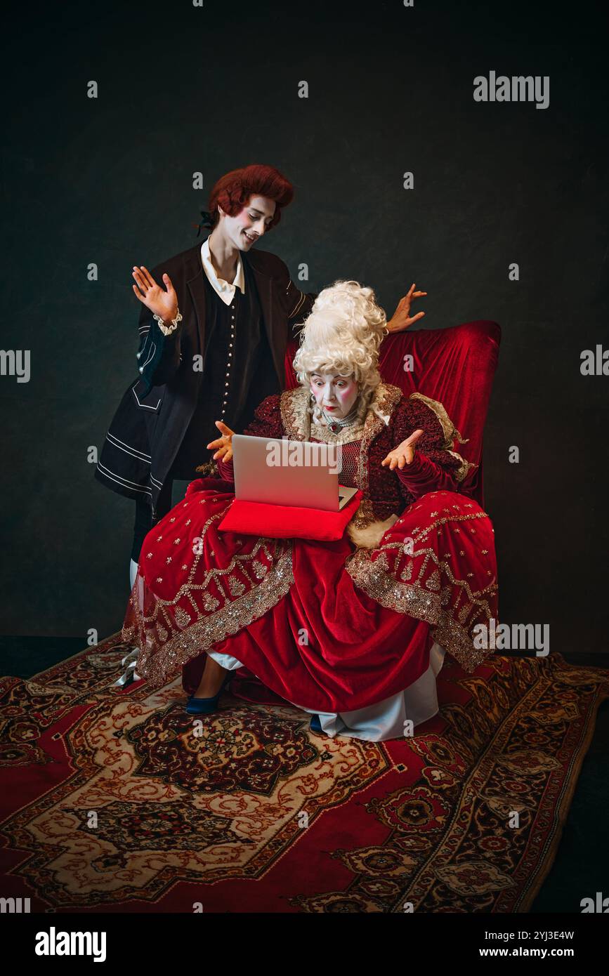 Impressed medieval elderly woman, royal empress looking on laptop with ...