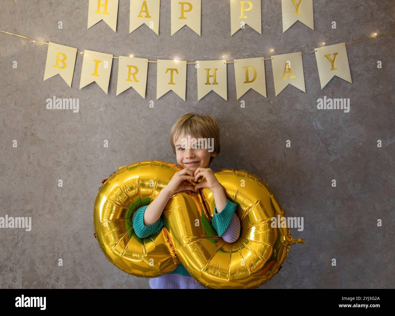 cheerful 8-year-old boy is holding a large golden holiday balloon in ...