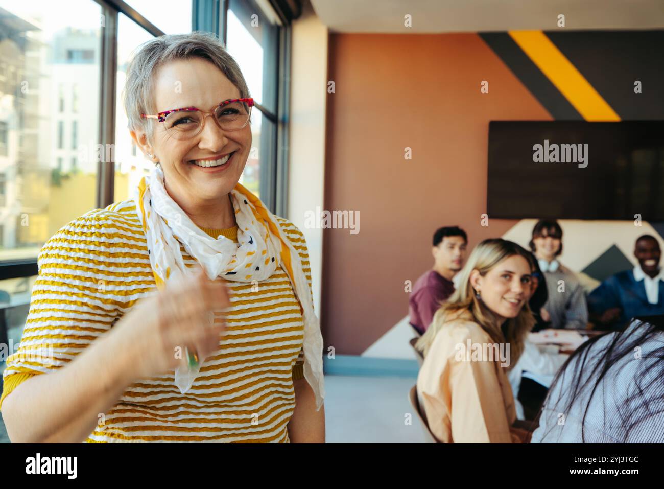 A mature female college lecturer interacts warmly with students in a ...