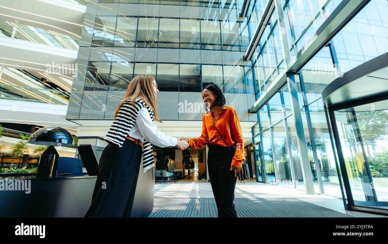 A welcoming scene of two professional women exchanging a friendly ...