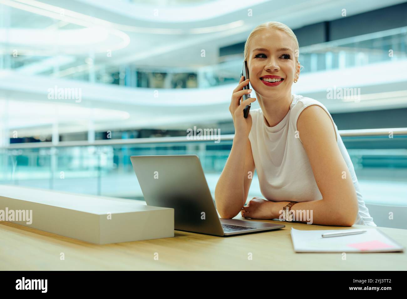 A smiling blonde salesperson sits in a modern office, engaging in a ...