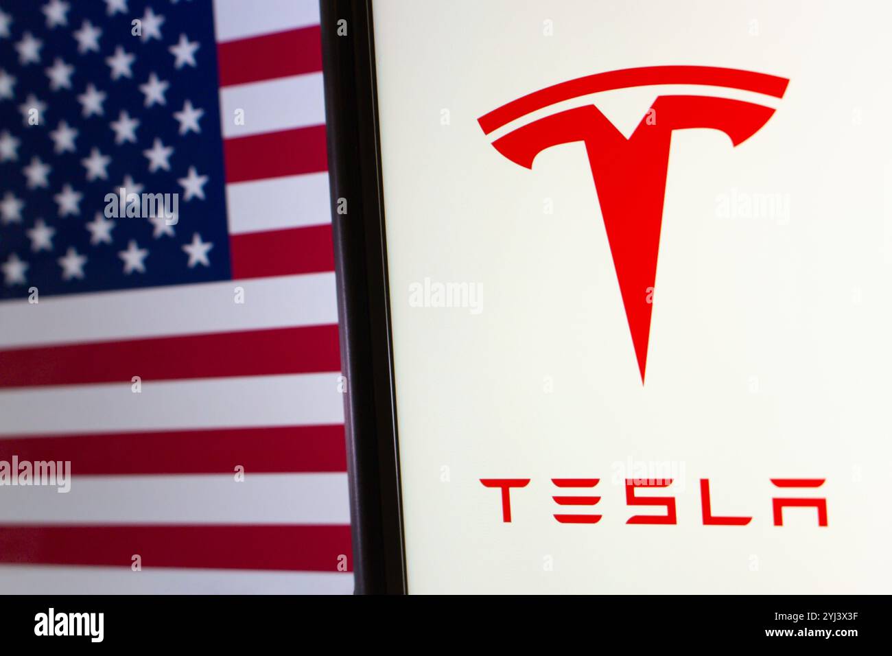 Tesla logo displayed on a screen with an US flag bg, symbolizing US EV ...