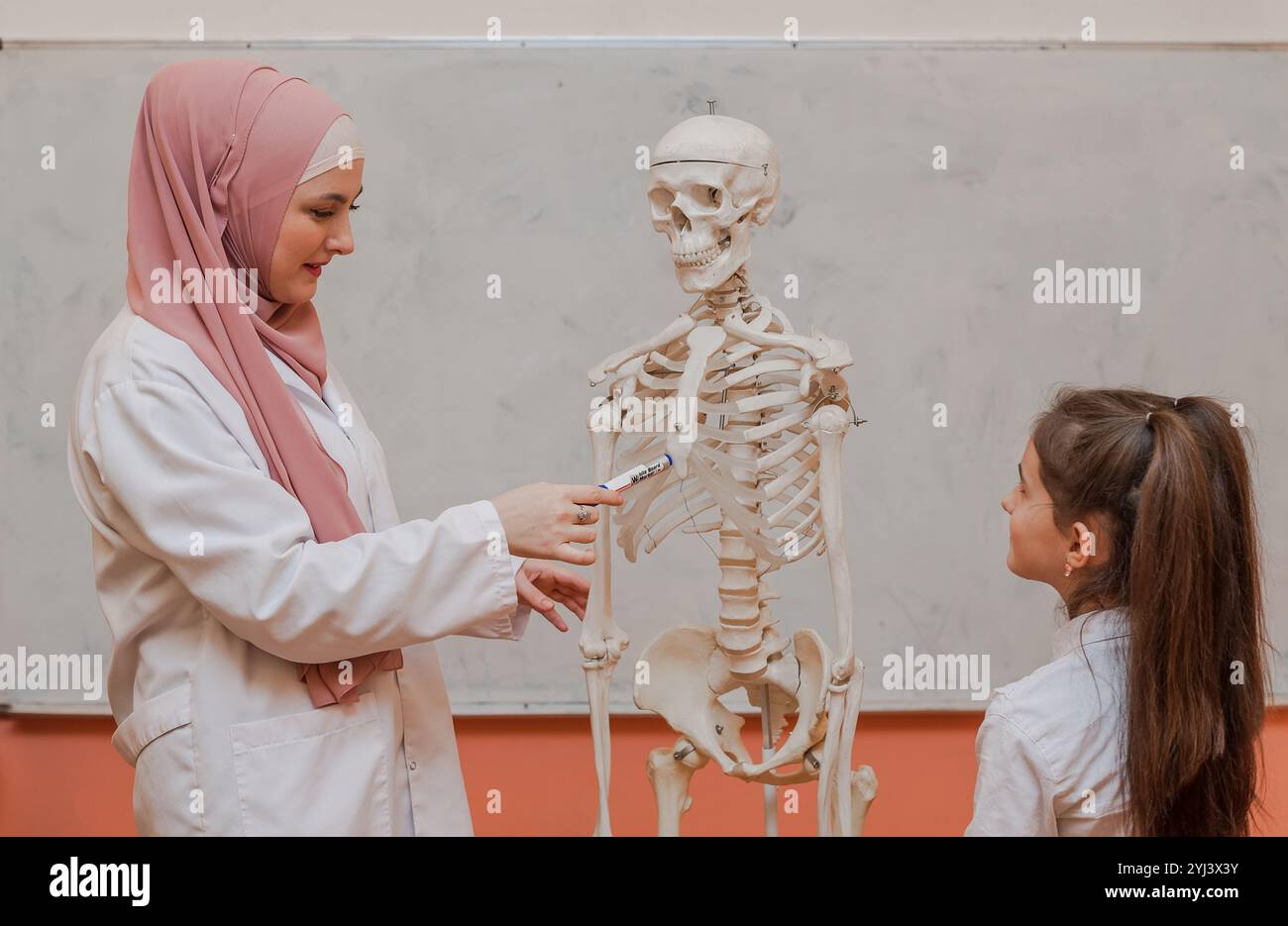 A Muslim female teacher teaches child students using the human body ...