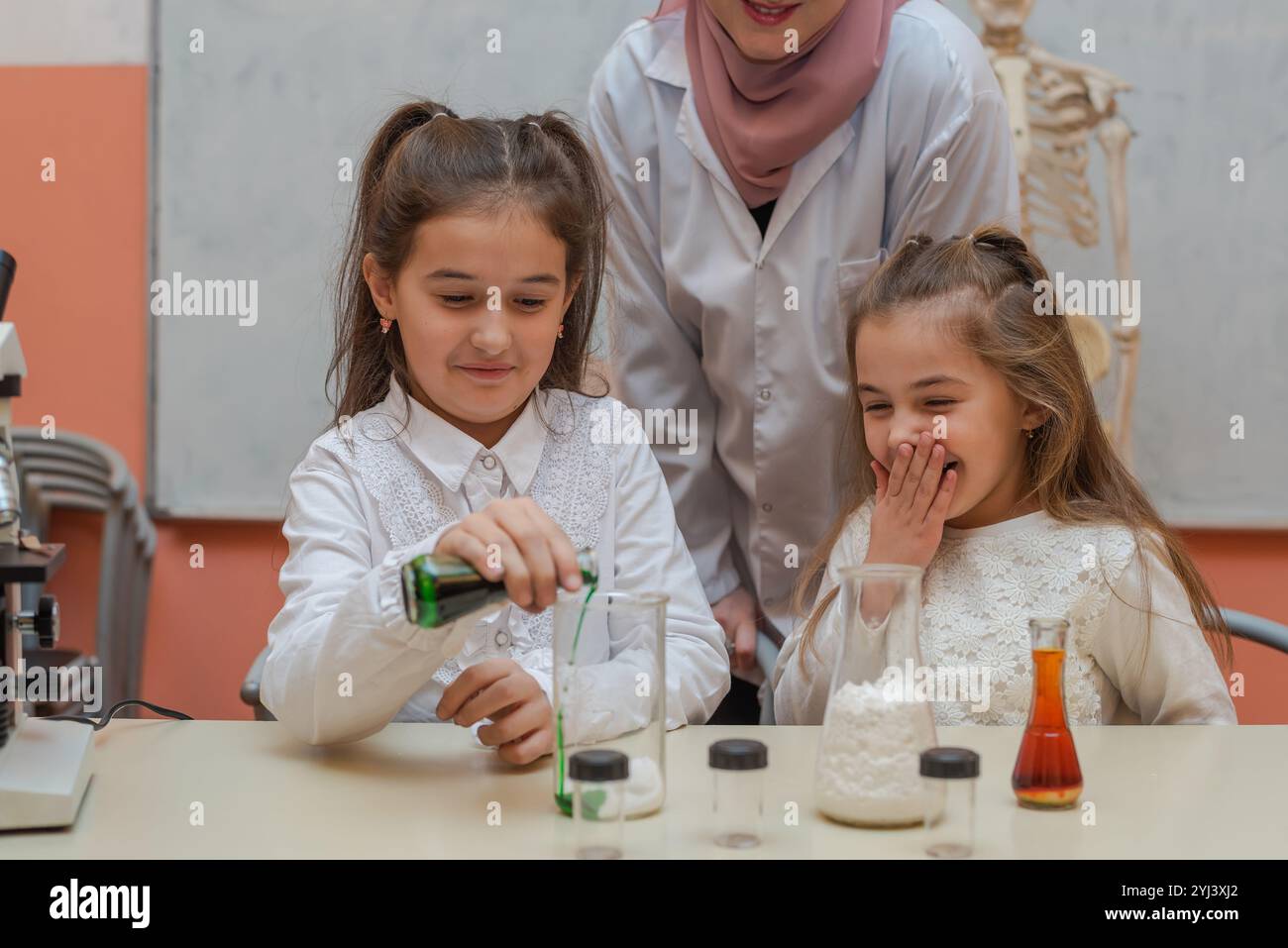 Kids scientists with a female Muslim teacher doing chemistry science ...