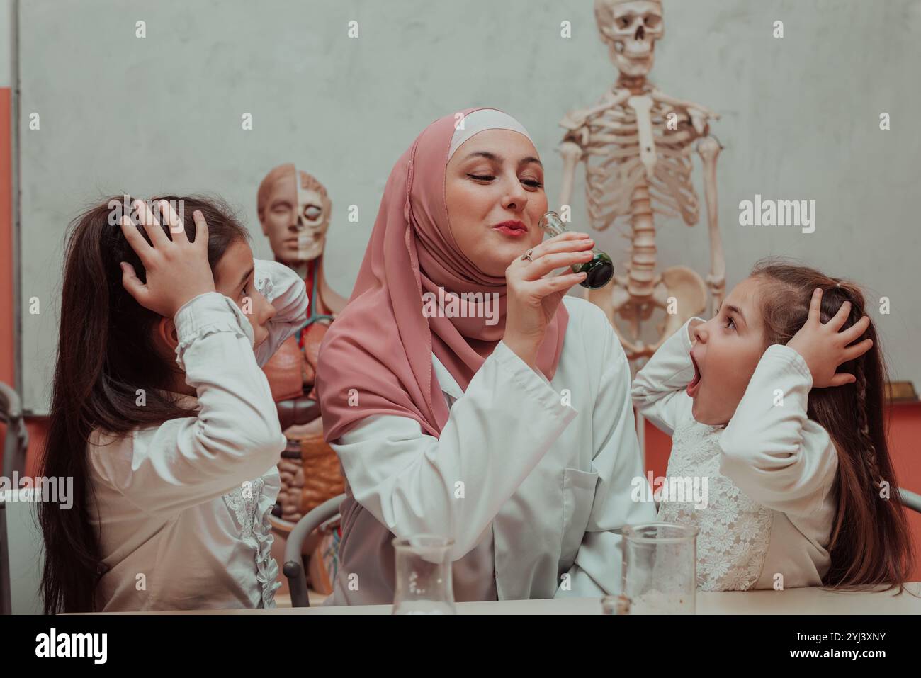 Kids scientists with a female Muslim teacher doing funny chemistry ...